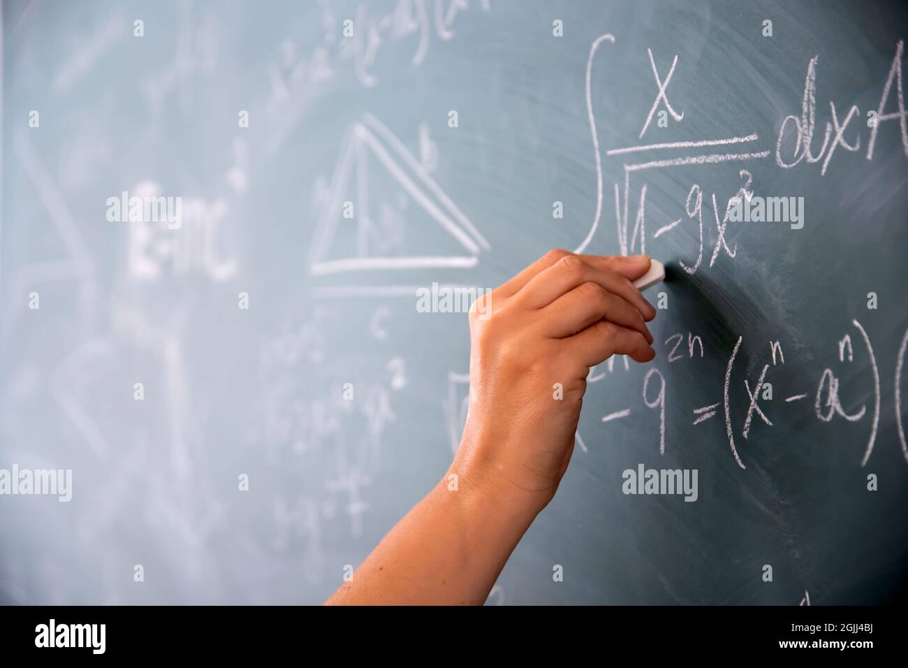 Close-up shot of a hand holding chalk and writing mathematical ...