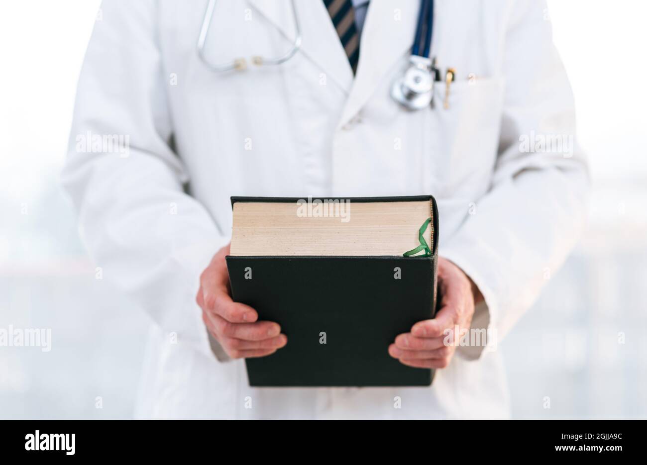 Doctor standing and holding a medical textbook Stock Photo - Alamy