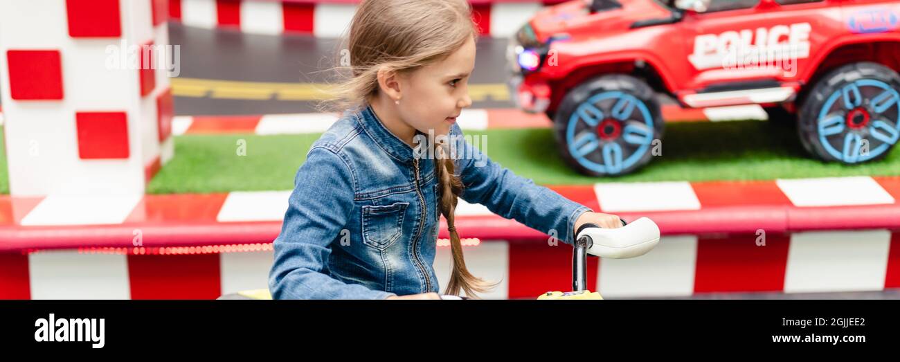 little happy kid girl fun riding an small electric cars on sport ground ...