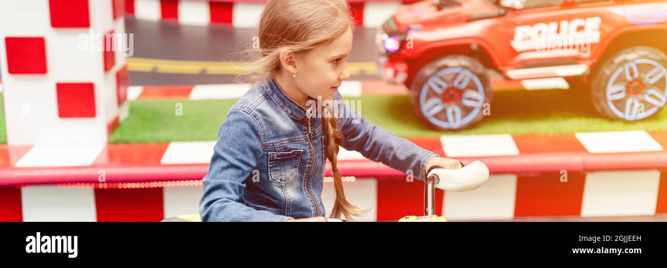 little happy kid girl fun riding an small electric cars on sport ground ...