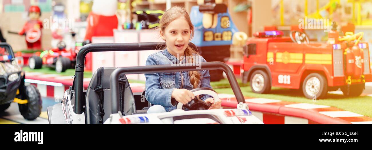 little happy kid girl fun riding an small electric cars on sport ground ...