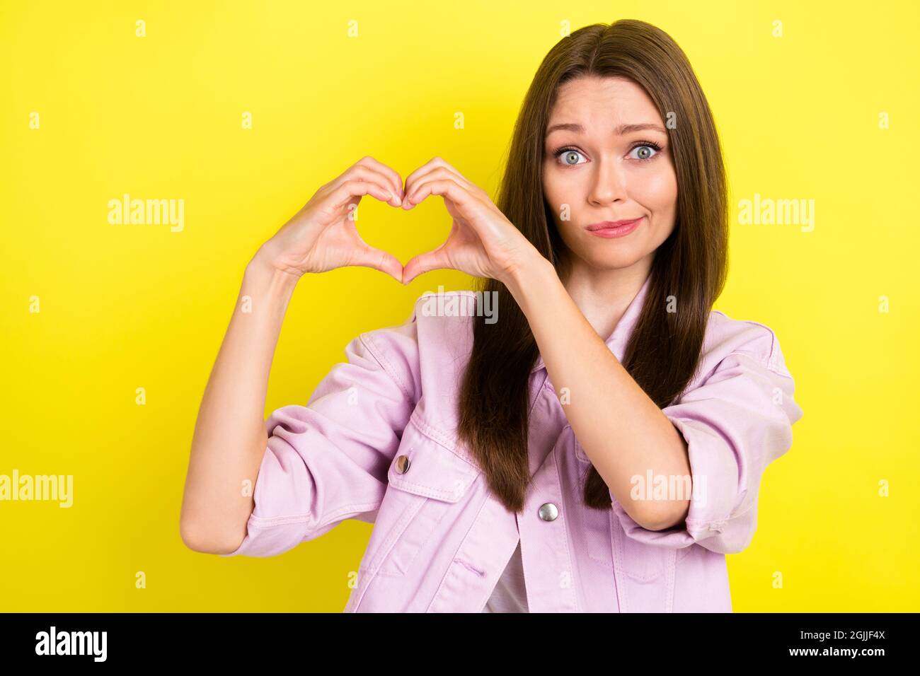 Portrait of attractive confused doubtful girl showing heart symbol ...