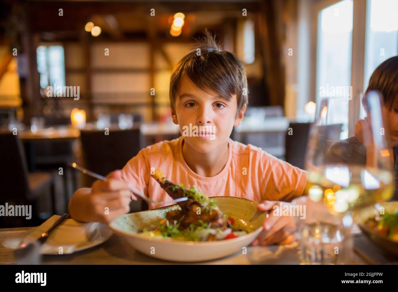 Preschool child, cute boy, eating lamb meat in a restaurant, cozy ...