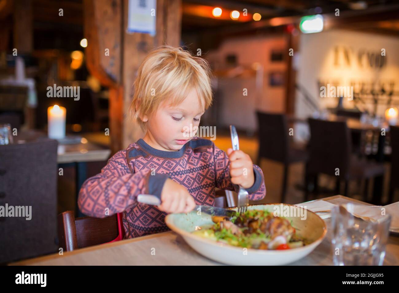 Preschool child, cute boy, eating lamb meat in a restaurant, cozy ...
