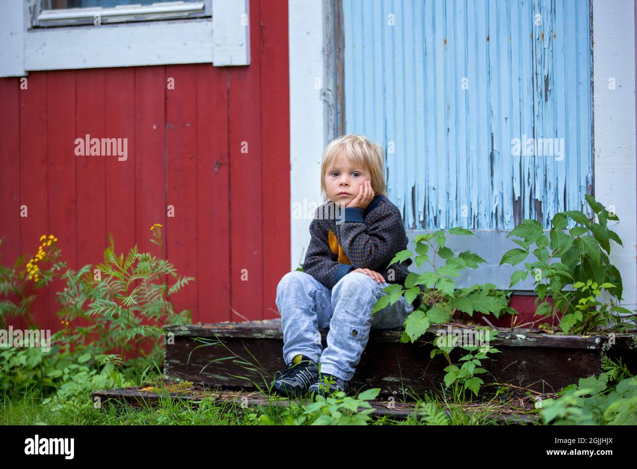 Sad little child, preschool boy, sitting on stairs in front of old ...