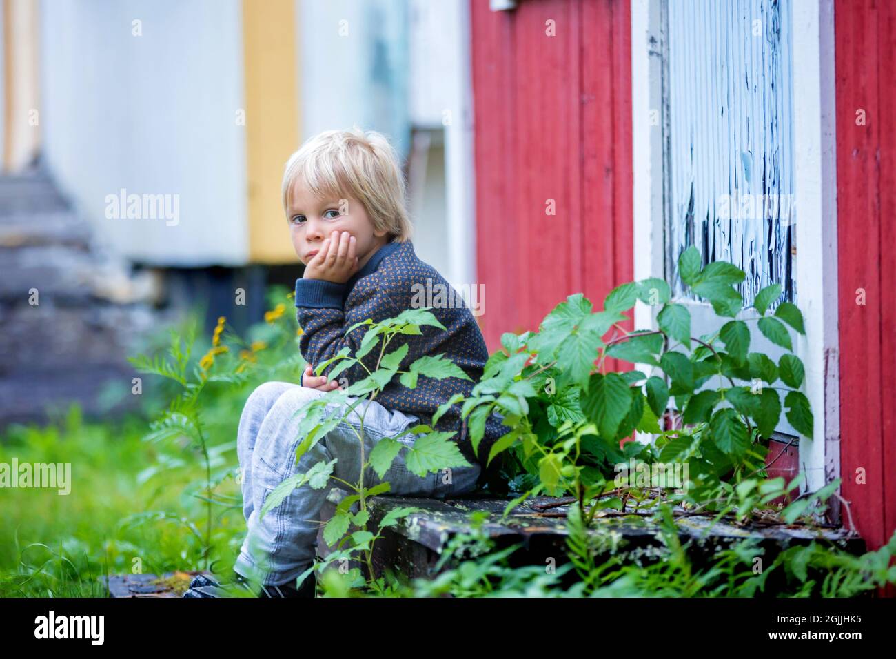 Sad little child, preschool boy, sitting on stairs in front of old ...