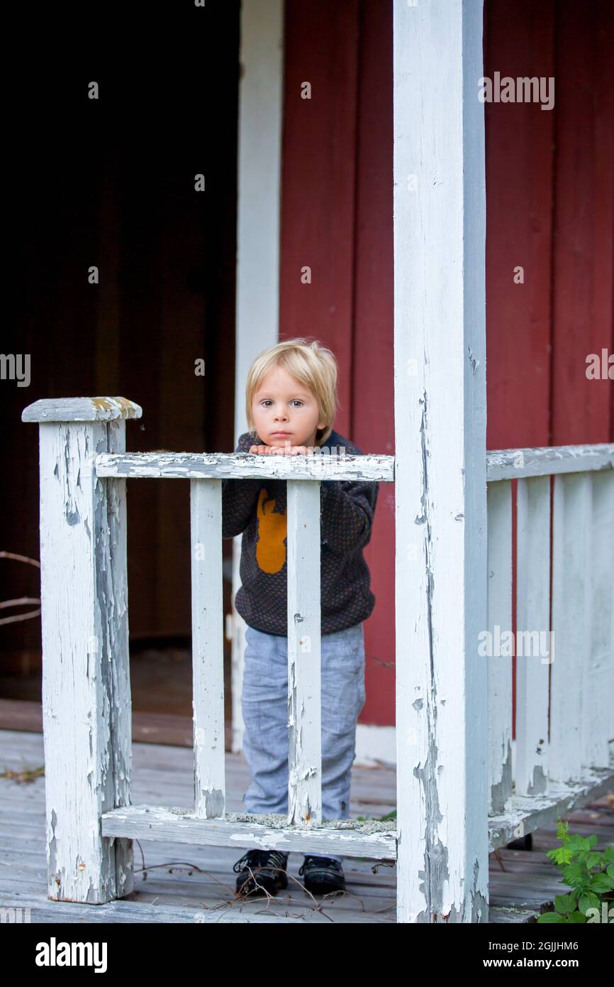 Sad little child, preschool boy, sitting on stairs in front of old ...