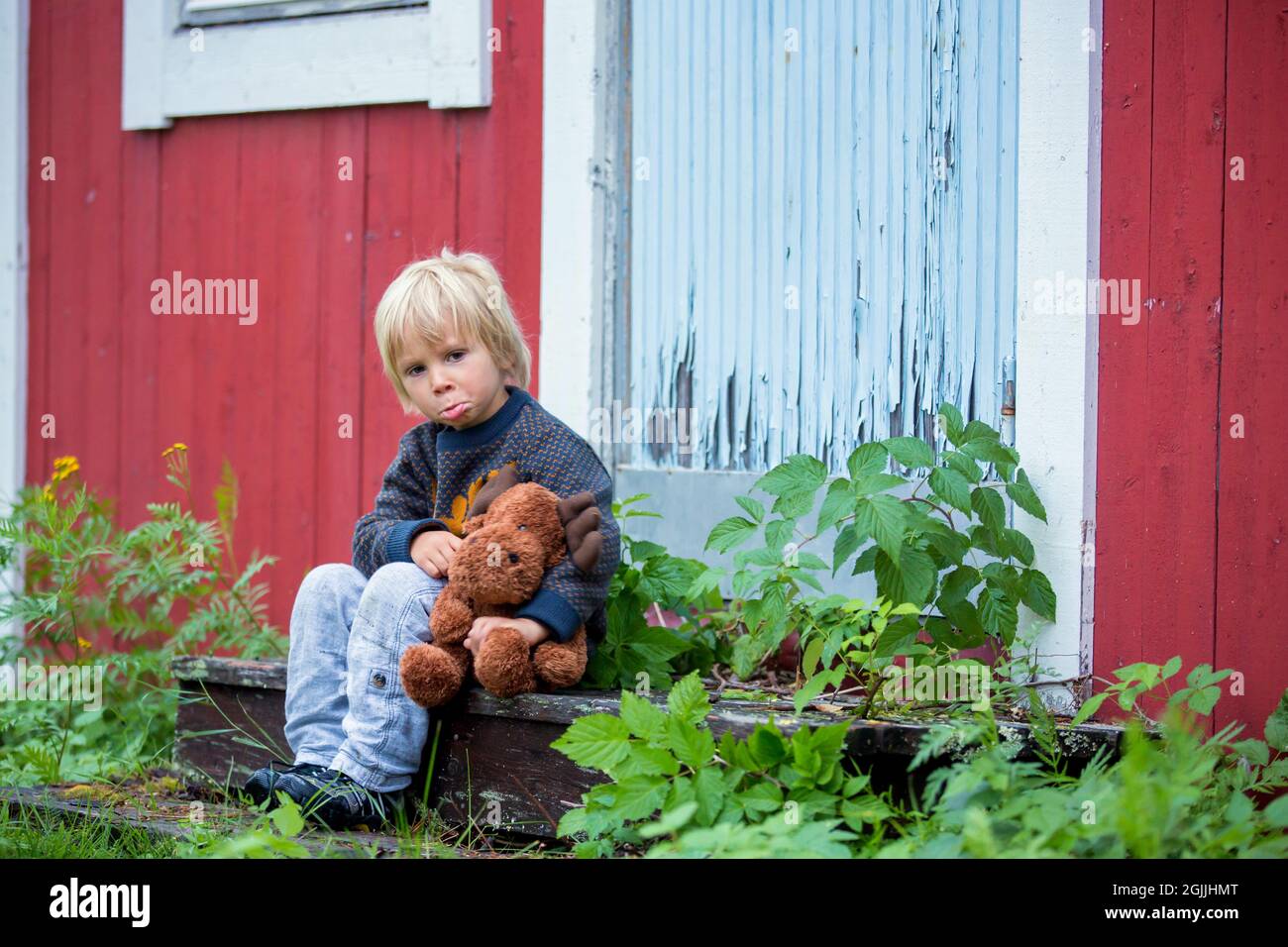 Sad little child, preschool boy, holding stuffed reindeer toy, sitting ...