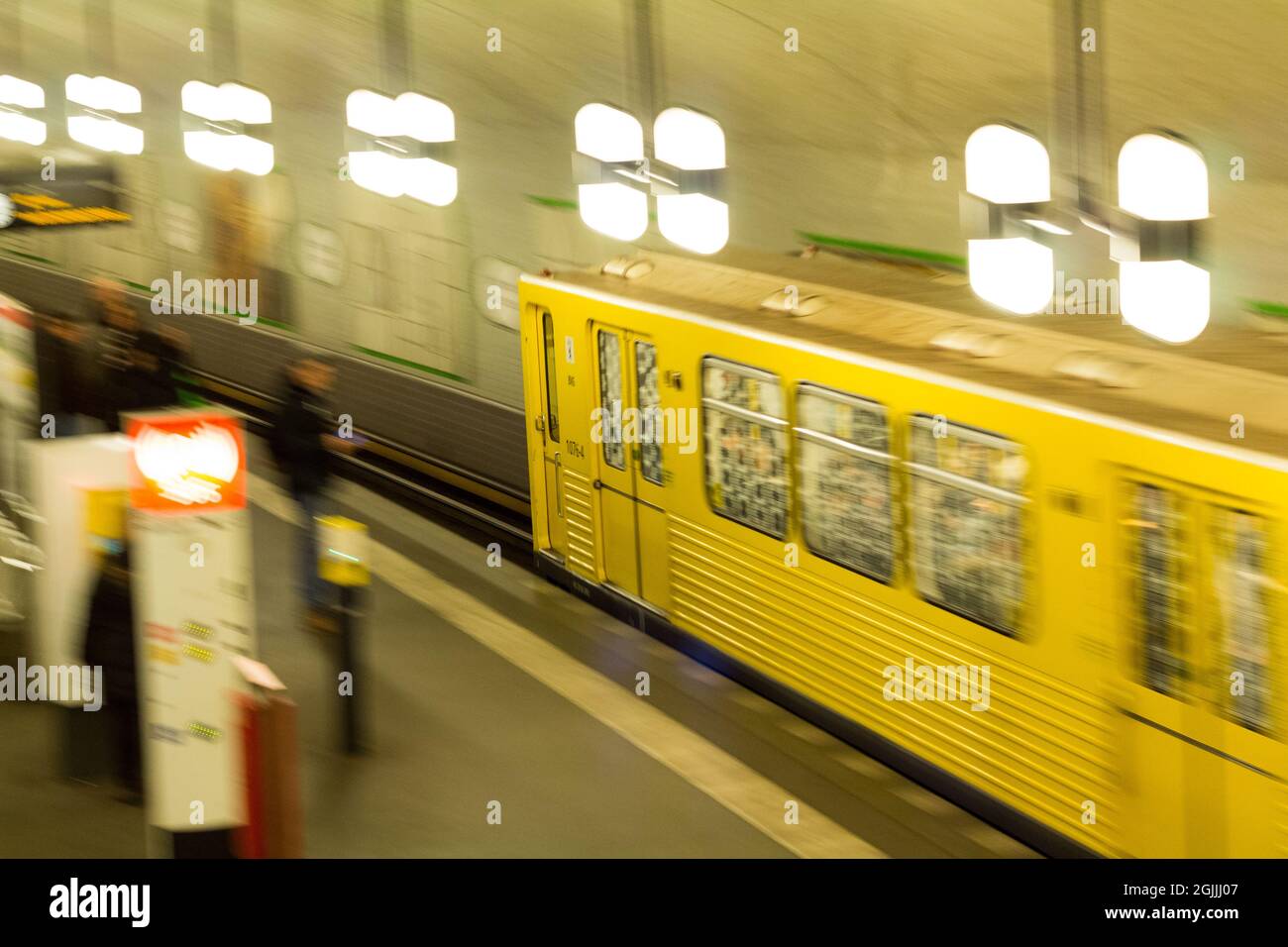 Yellow subway train speeding through a bustling underground station ...