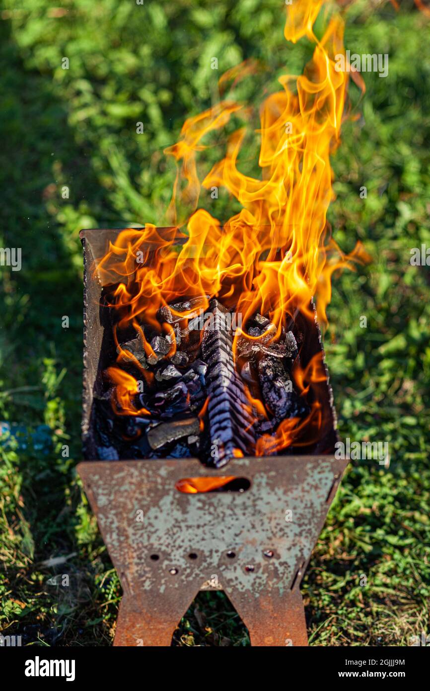 The firewood in the grill burns with a bright orange flame of fire on a ...
