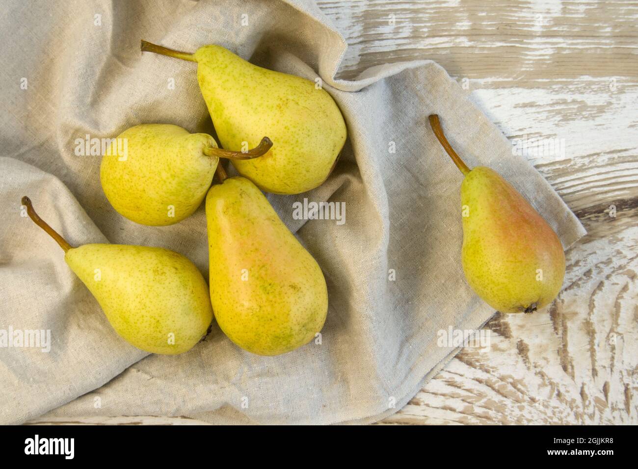 Green yellow pears in brown bowl on rough wooden background, top view ...