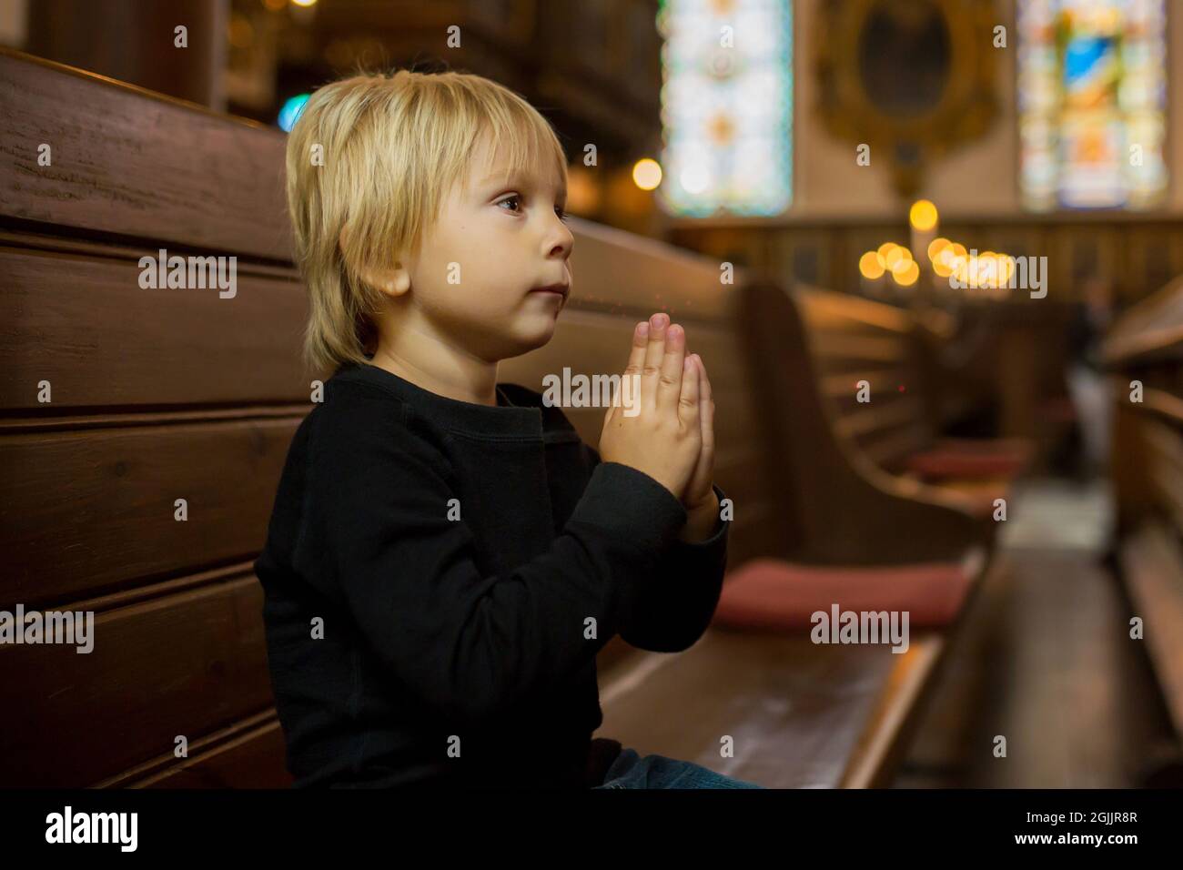 Little child, boy, praying in church, cathedrale in Stockholm, Sweden ...