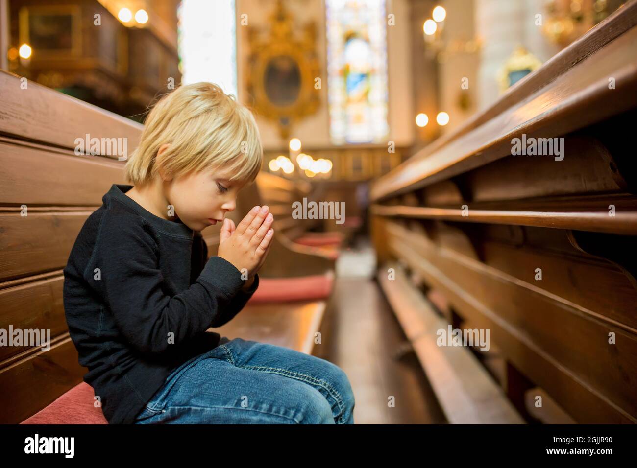 Little child, boy, praying in church, cathedrale in Stockholm, Sweden ...