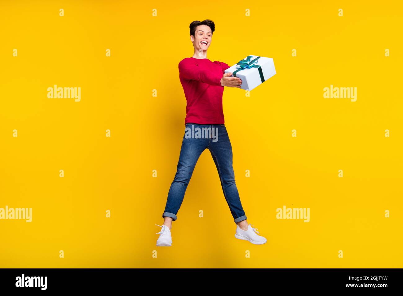 Photo of funny adorable young guy dressed red sweater holding present ...