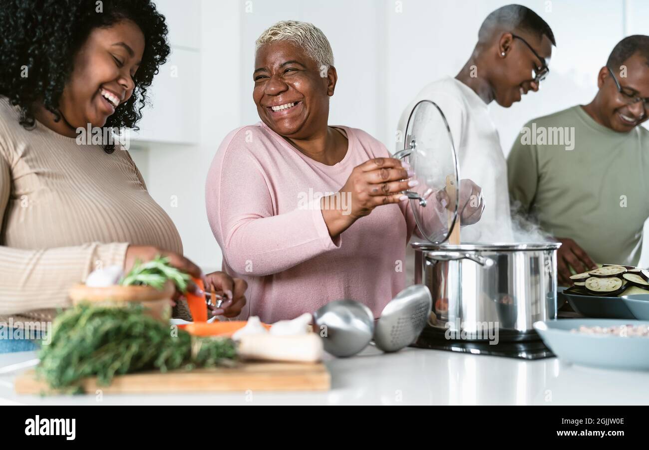 Happy African family having fun in modern kitchen preparing food recipe ...