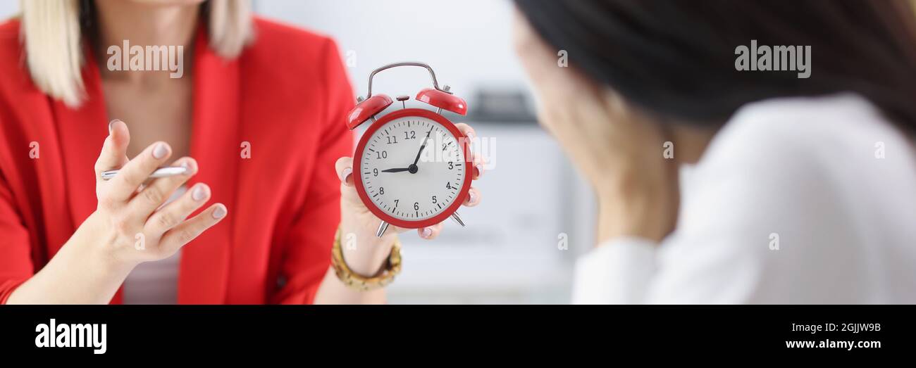 Manager shows alarm clock to subordinate, fixing delay for work Stock ...