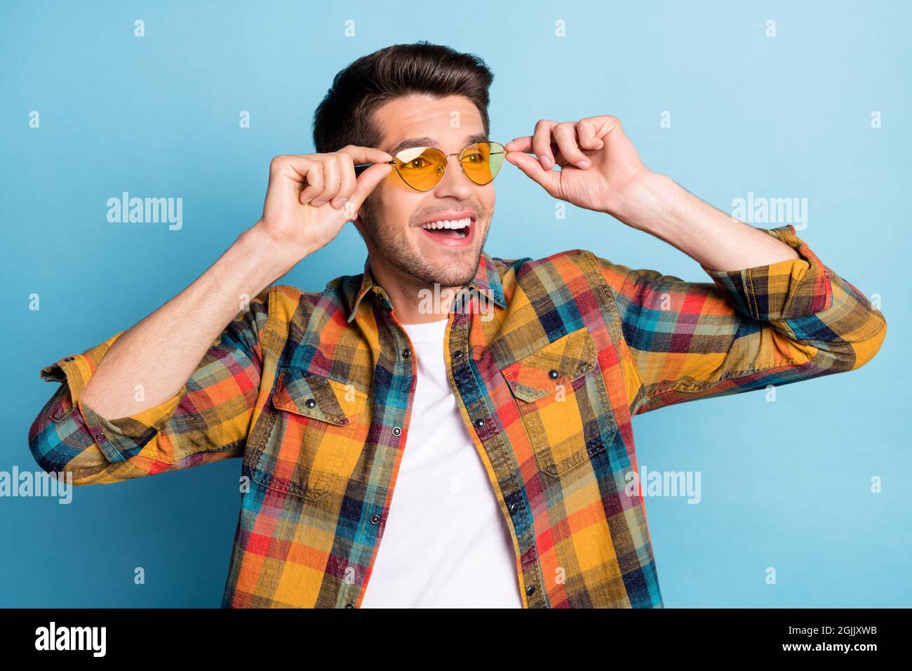 Portrait of attractive amazed cheerful guy touching specs looking far ...