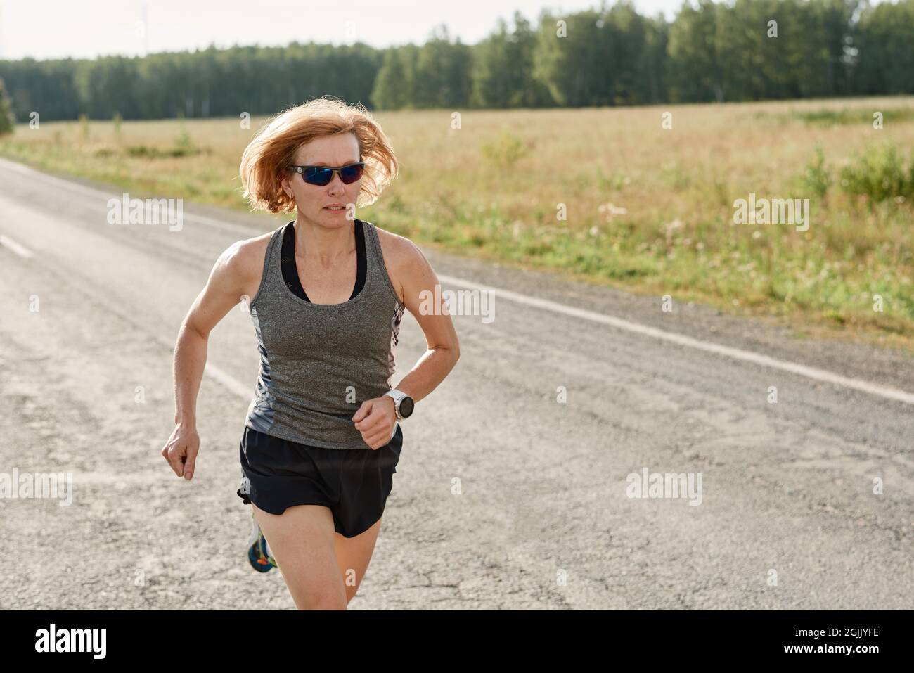 Female athlete running on a road she preparing for her competition ...