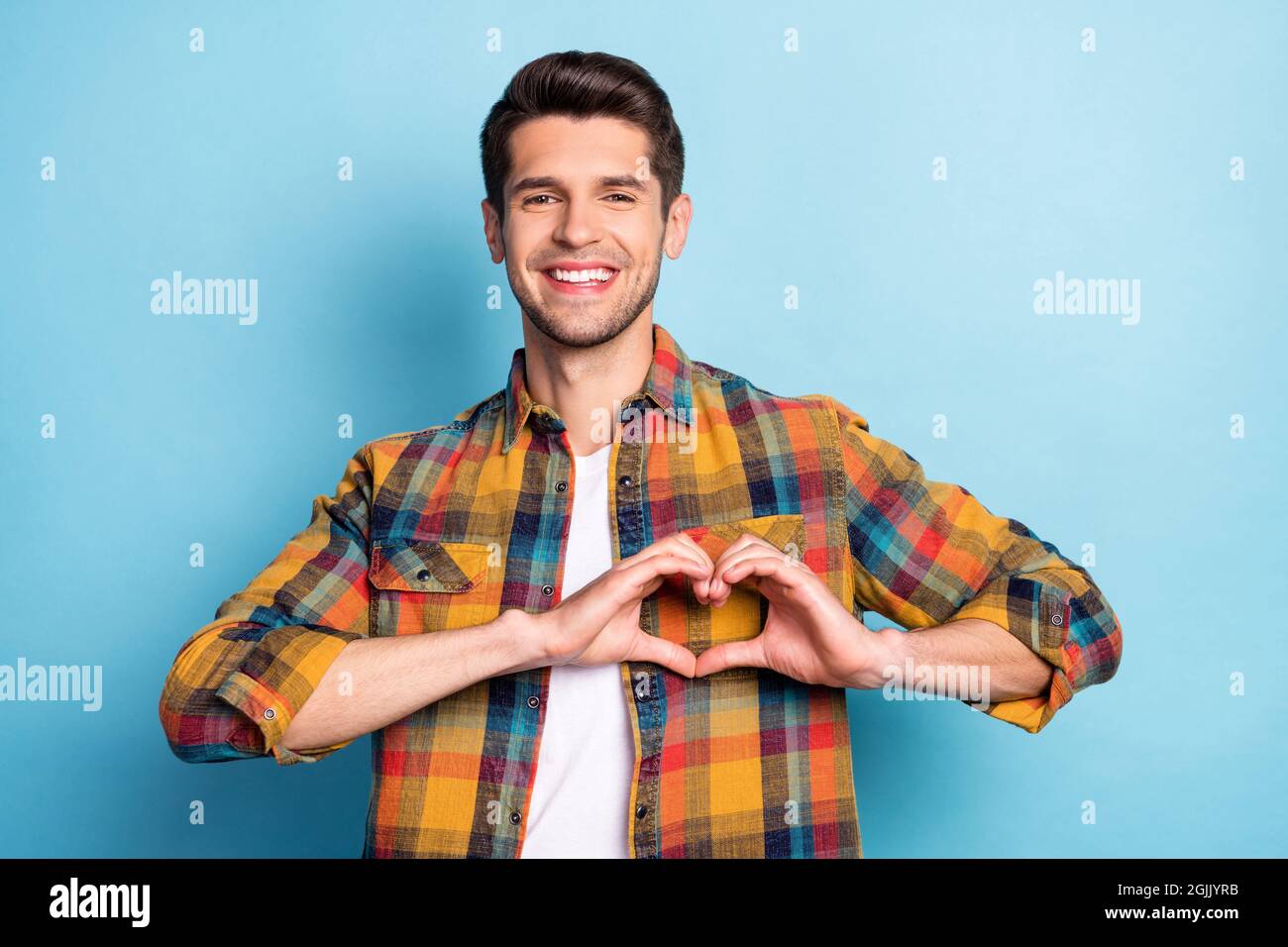 Portrait of attractive cheerful affectionate guy showing heart sign ...