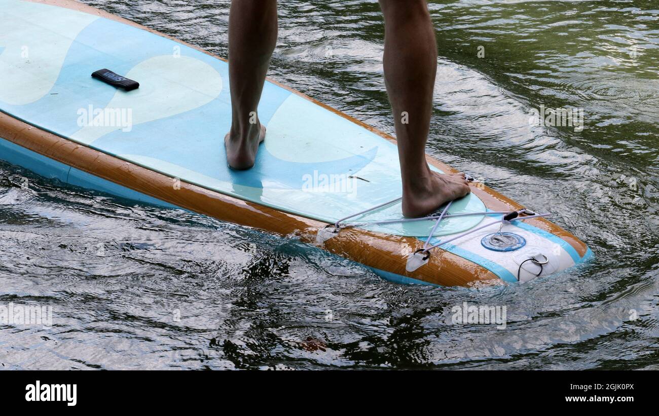 Shot of human legs on a paddleboard in the water Stock Photo - Alamy