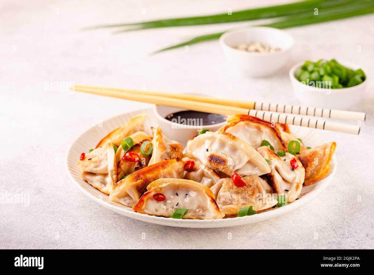 Fried dumplings served with green onions, sesame seeds and chili ...