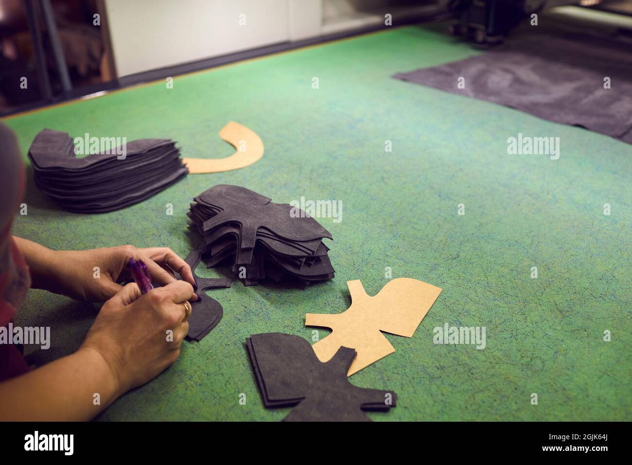 Shoe factory worker making design for new boots standing at table with ...