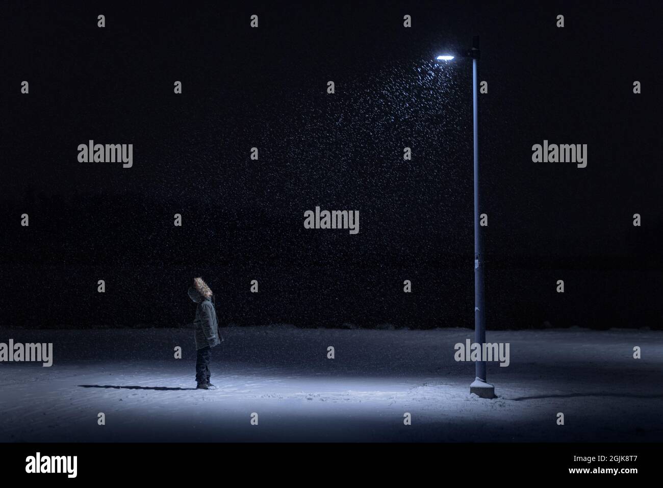 a boy and the lamp post in snowy night Stock Photo - Alamy