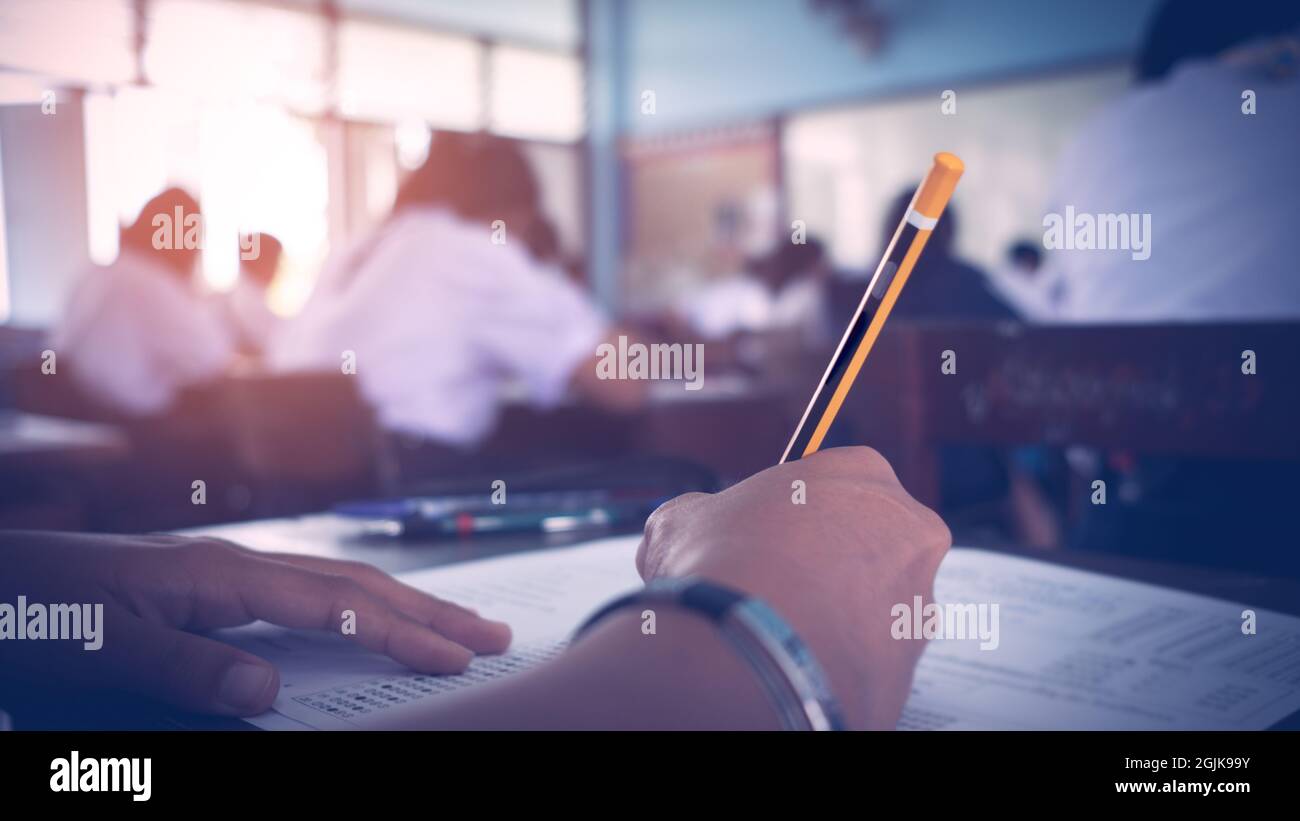 Students writing and reading exam answer sheets exercises in classroom ...