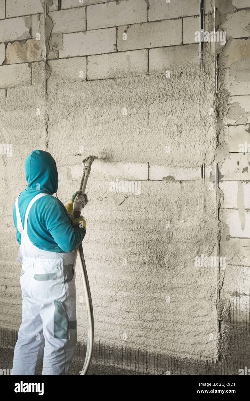 The process of applying plaster to walls inside a building by machine ...