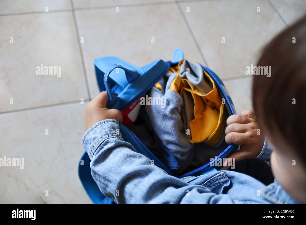 Little child kid unpacks opens bagpack prepares for fligt journey trip ...