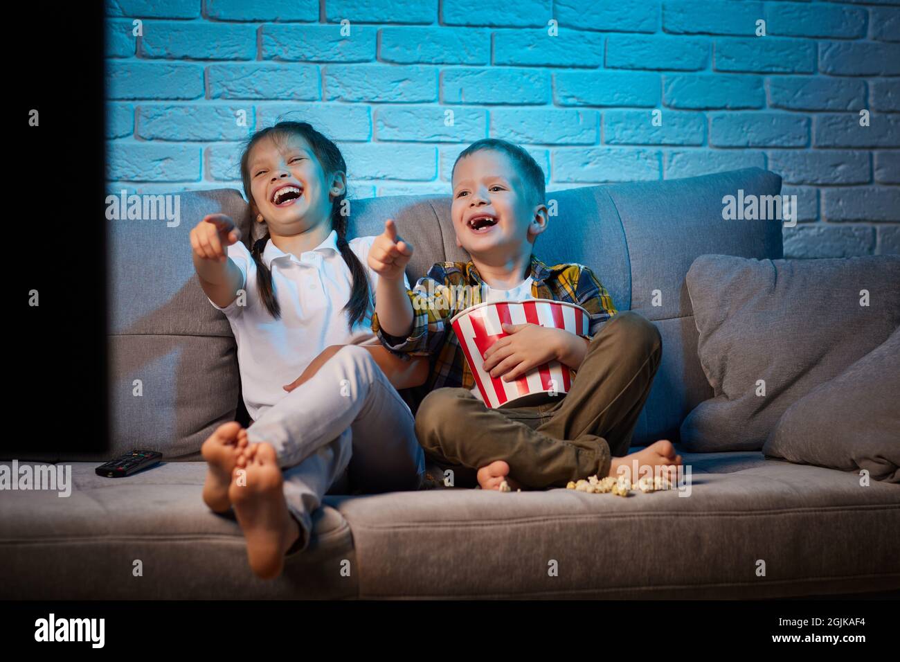 two children with remote control watching TV Stock Photo - Alamy