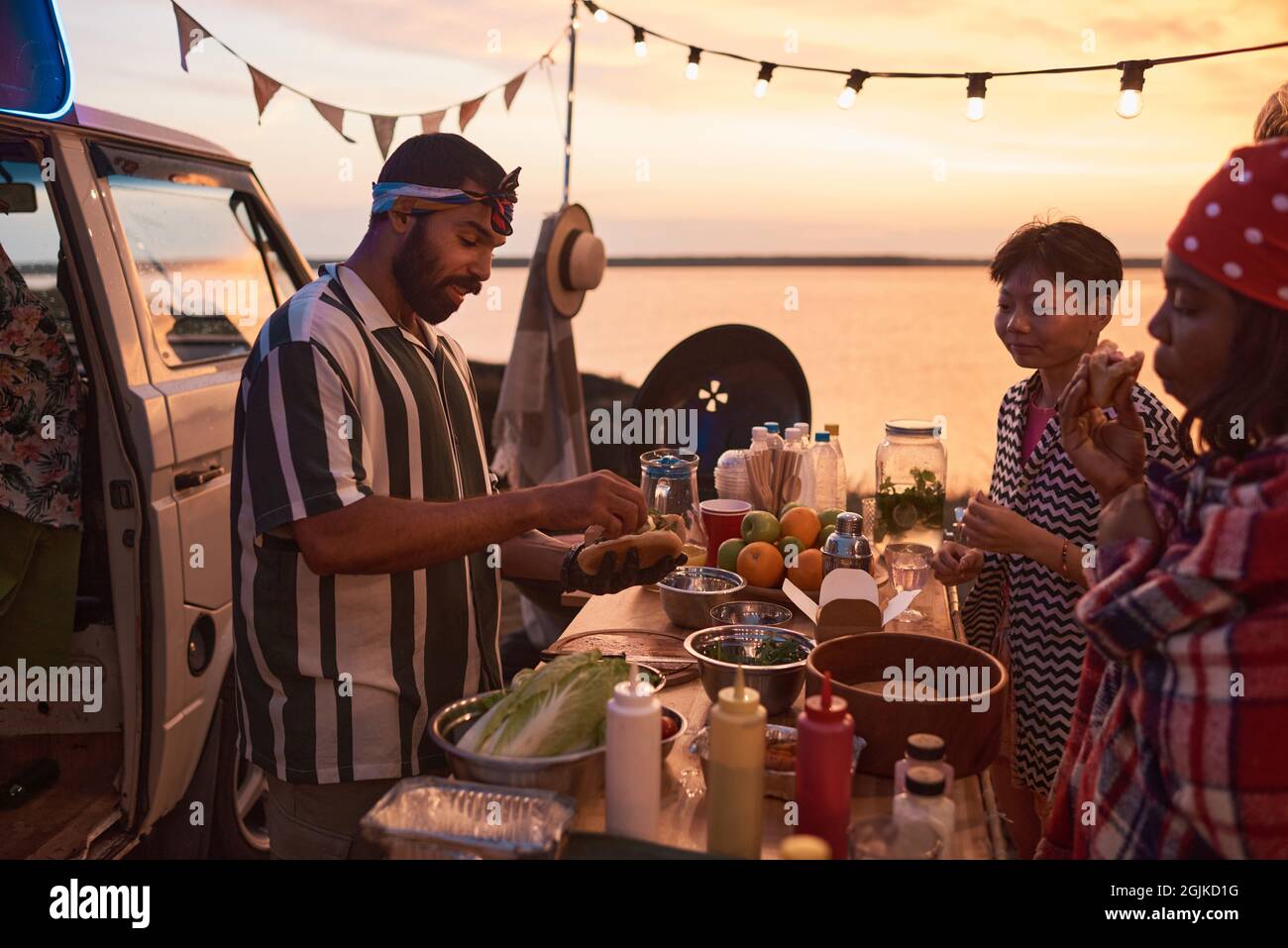 Young people eating fast food while young man preparing it for them ...