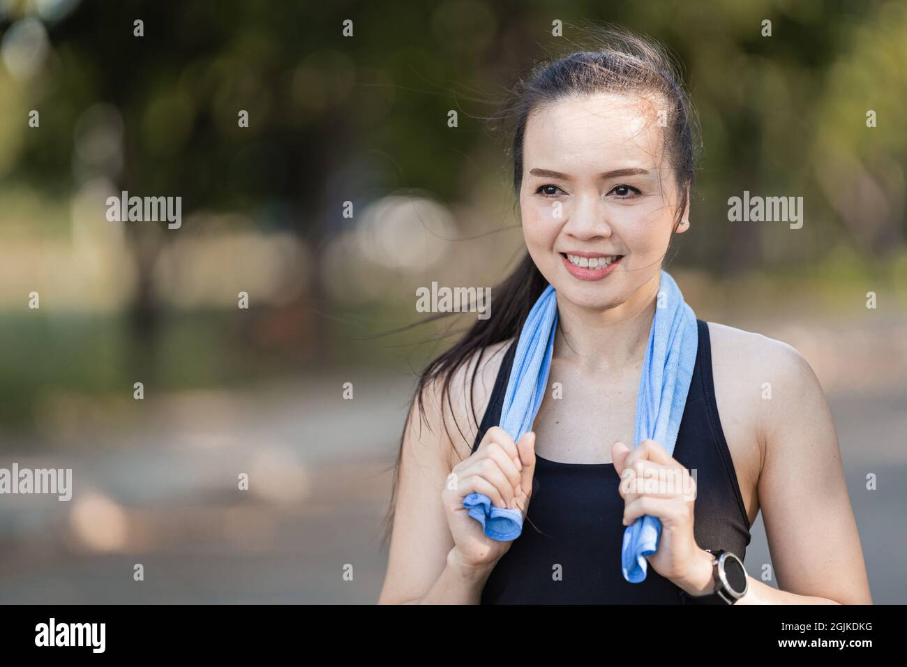 Healthy happy Asian runner in a black outfit jogging in a park during ...