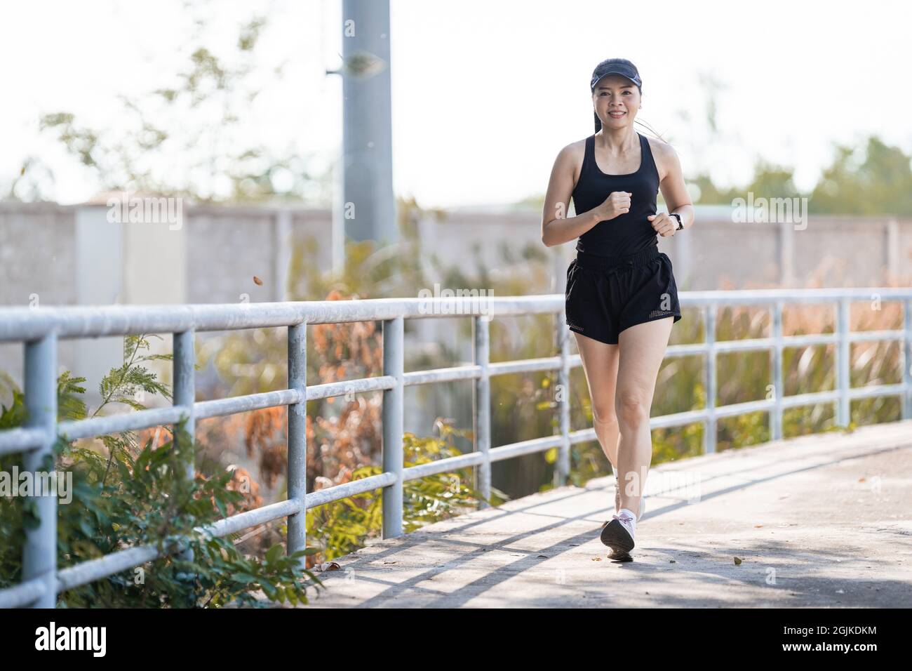 Healthy happy Asian runner in a black outfit jogging in a park during ...