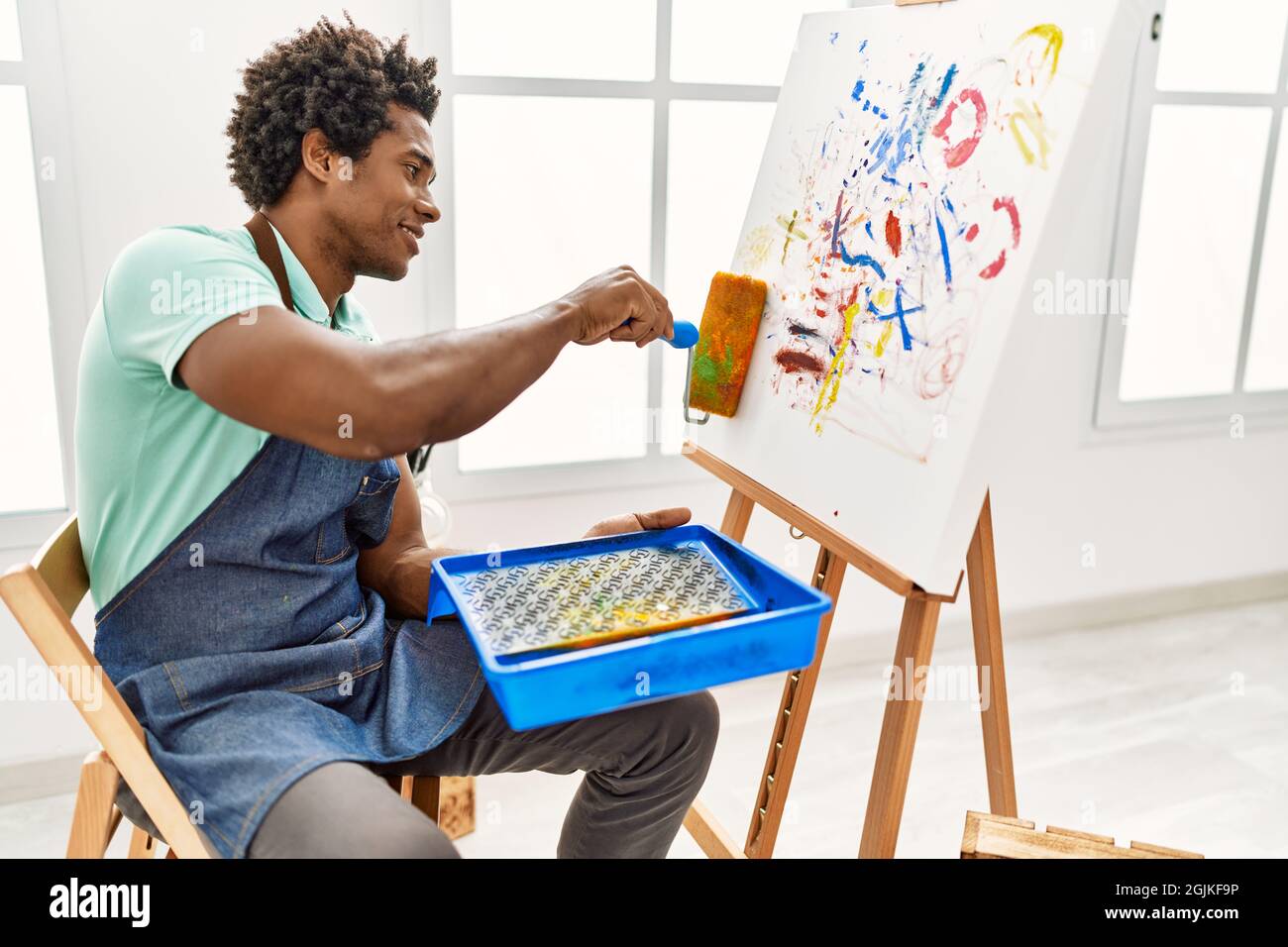 Young african american artist man drawing using paint roller at art ...