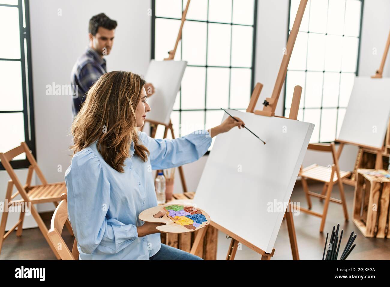 Two hispanic students painting at art school. Man looking partner draw ...