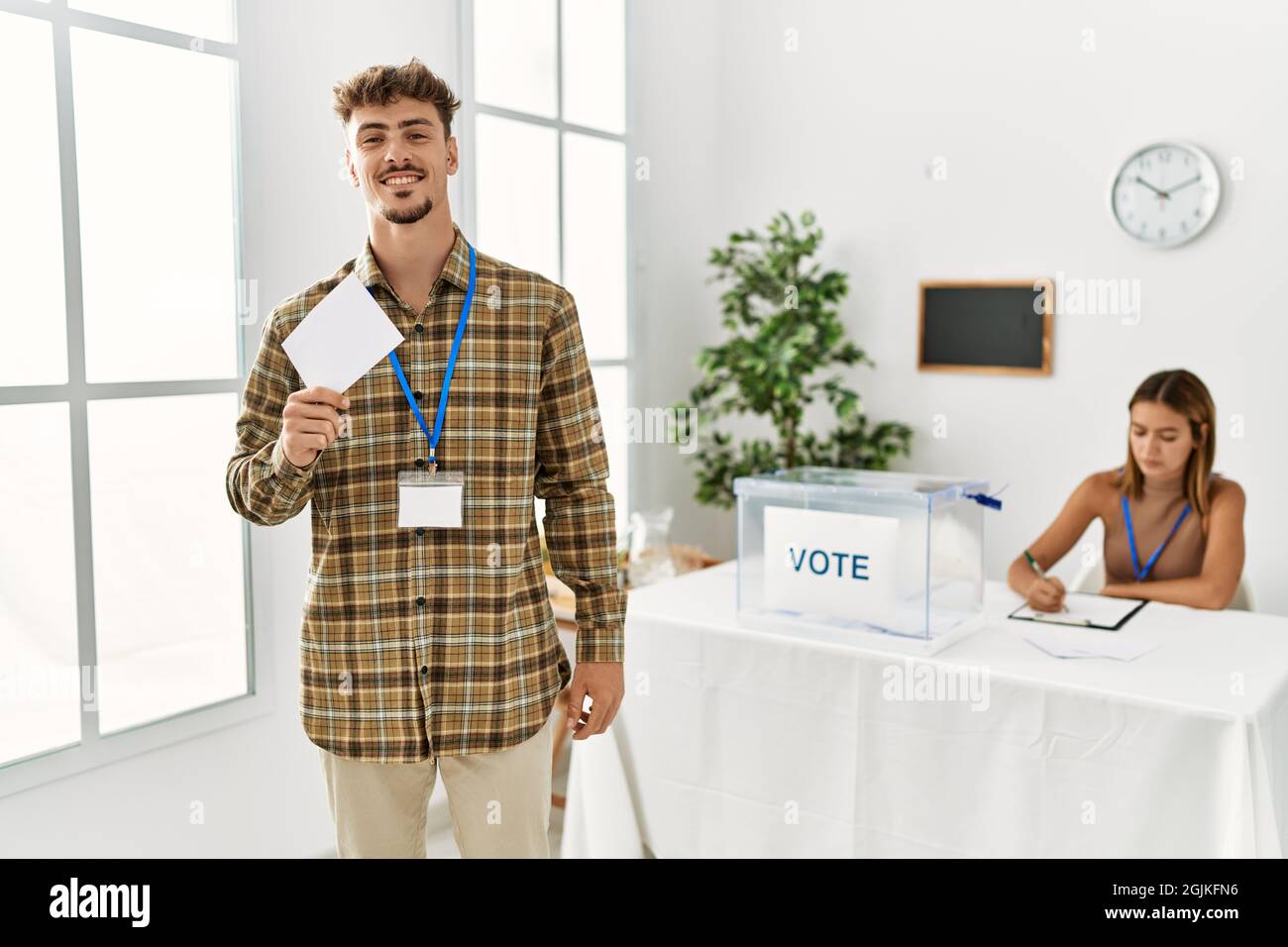 Young handsome man voting putting envelop in ballot box looking ...