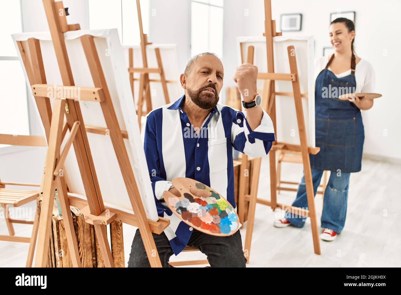 Senior artist man at art studio angry and mad raising fist frustrated ...