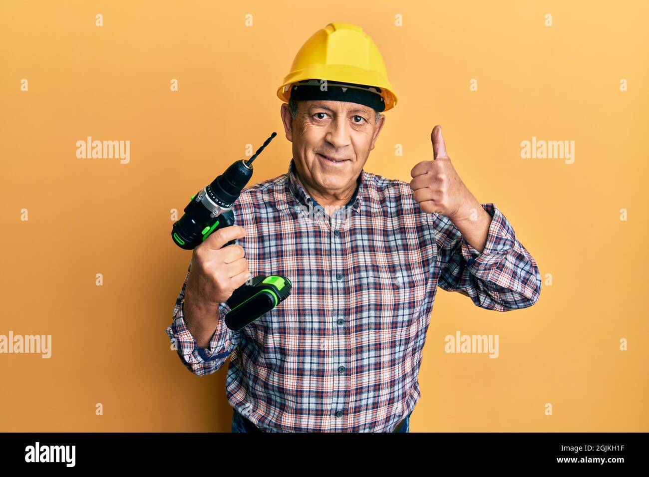 Handsome senior man with grey hair holding electric screwdriver wearing ...