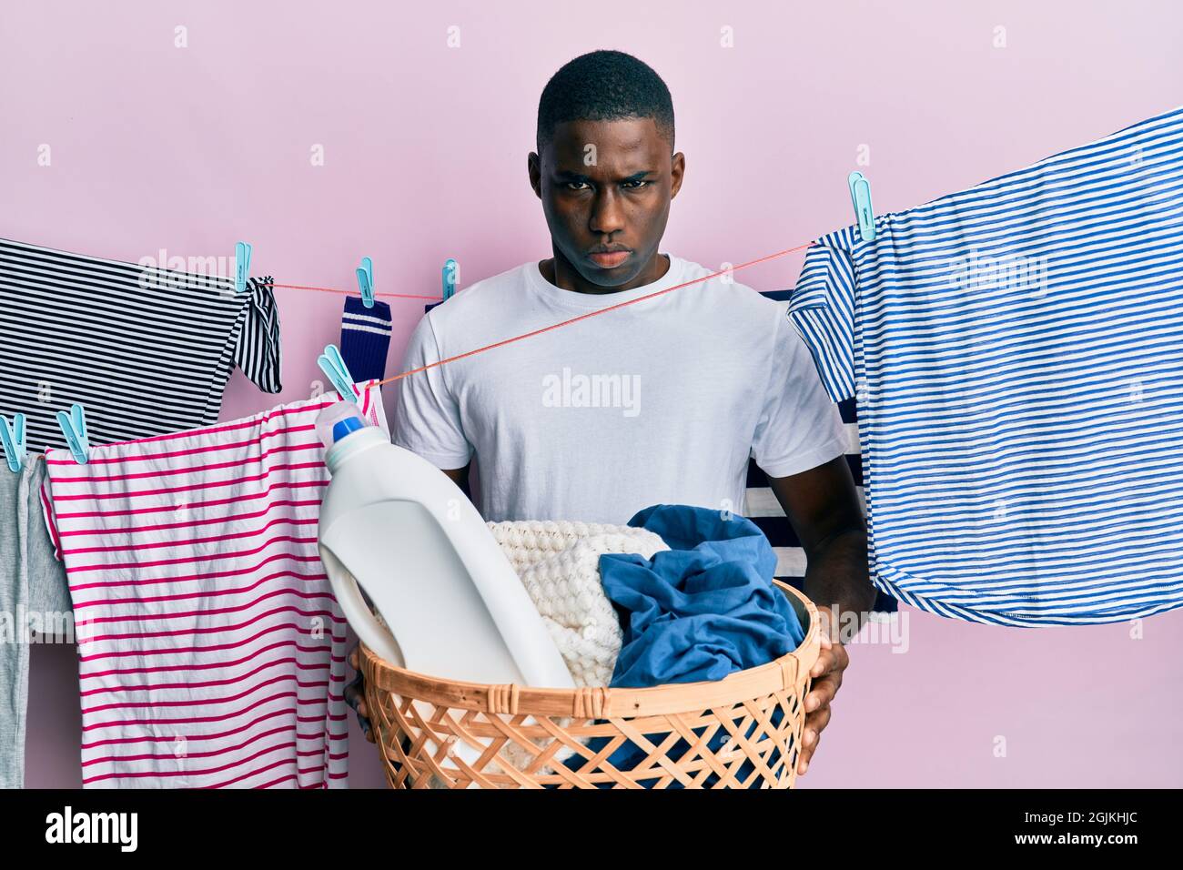 Young african american man holding laundry basket skeptic and nervous ...