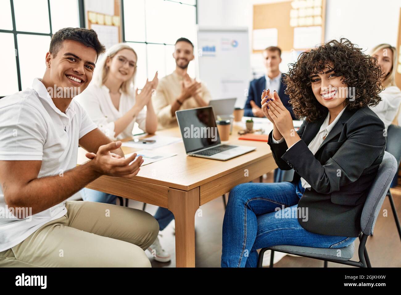 Group of young business workers clapping and looking to the camera at ...