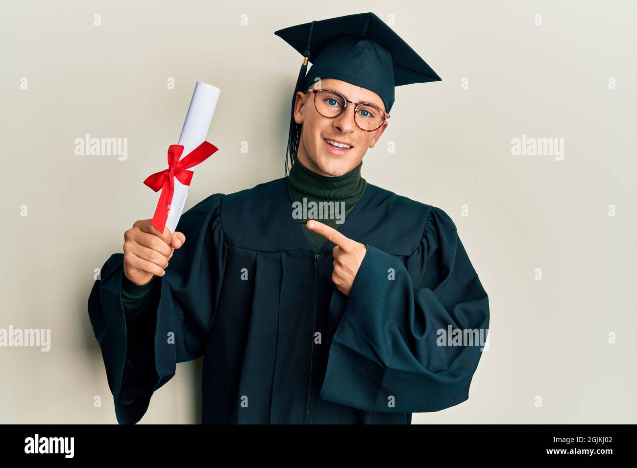 Young caucasian man wearing graduation cap and ceremony robe holding ...