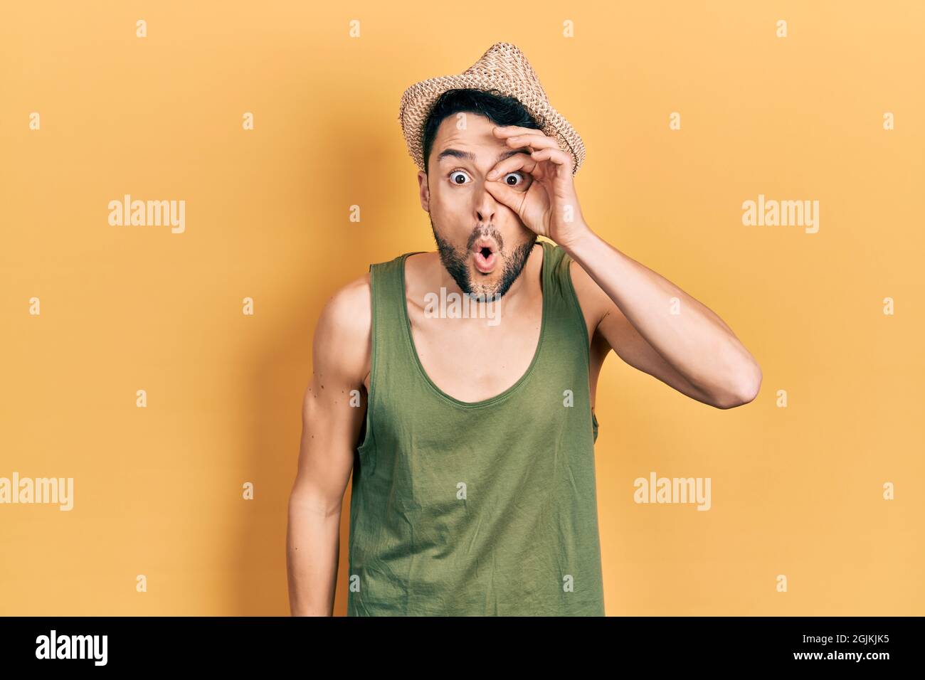 Young hispanic man wearing summer hat doing ok gesture shocked with ...