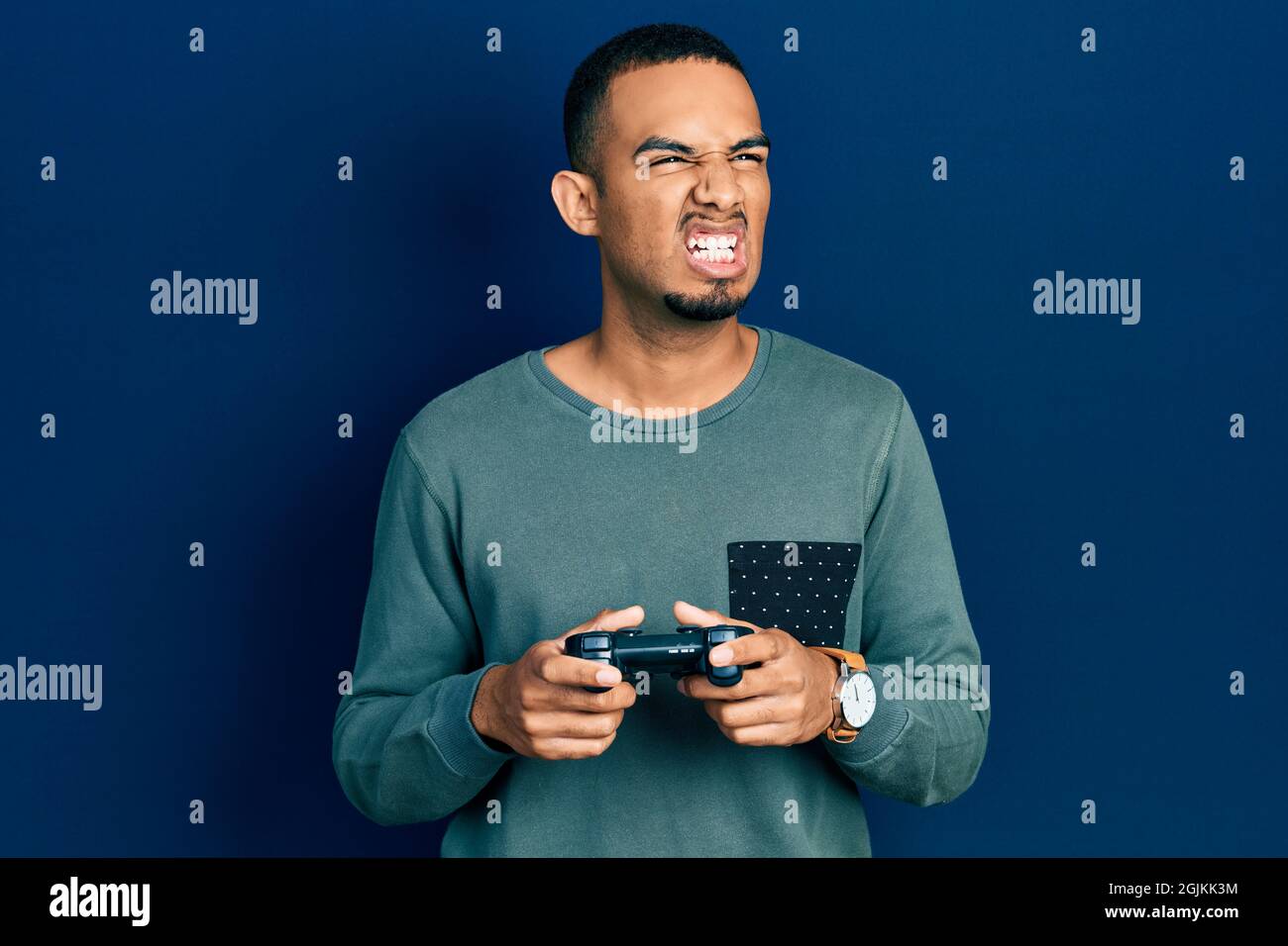 Young african american man playing video game holding controller angry ...