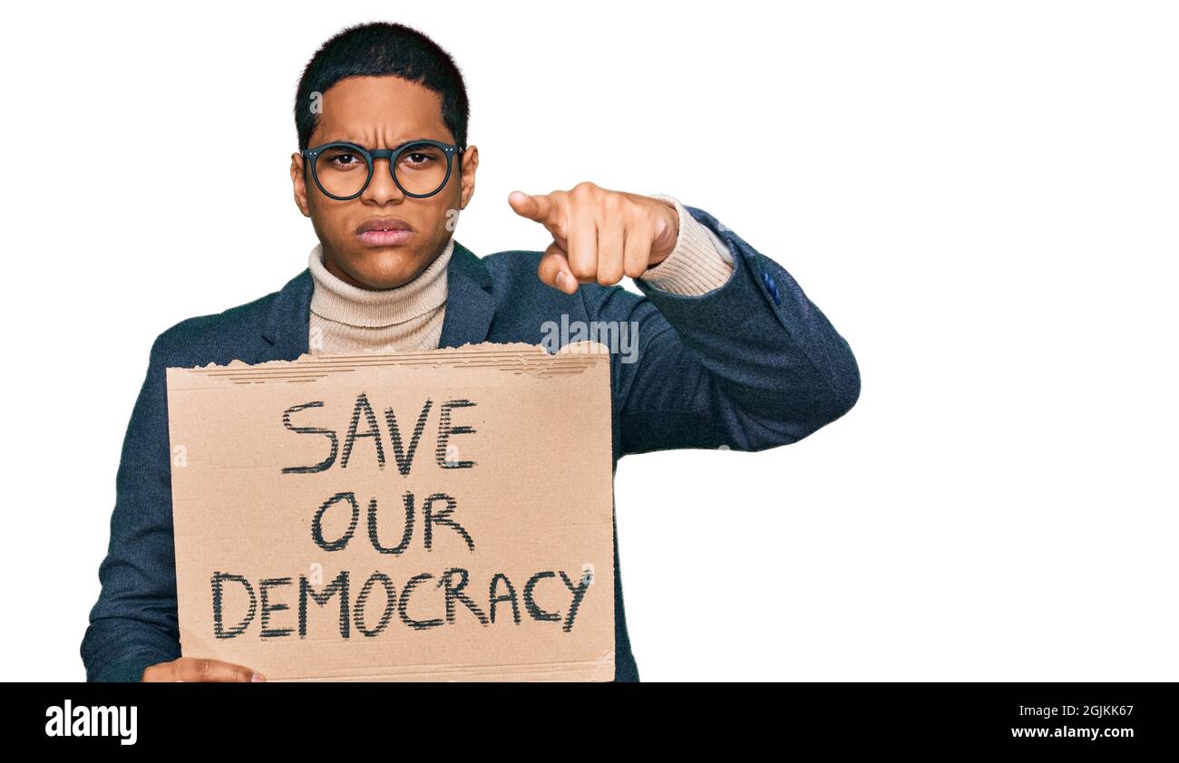 Young handsome hispanic man holding save our democracy protest banner ...