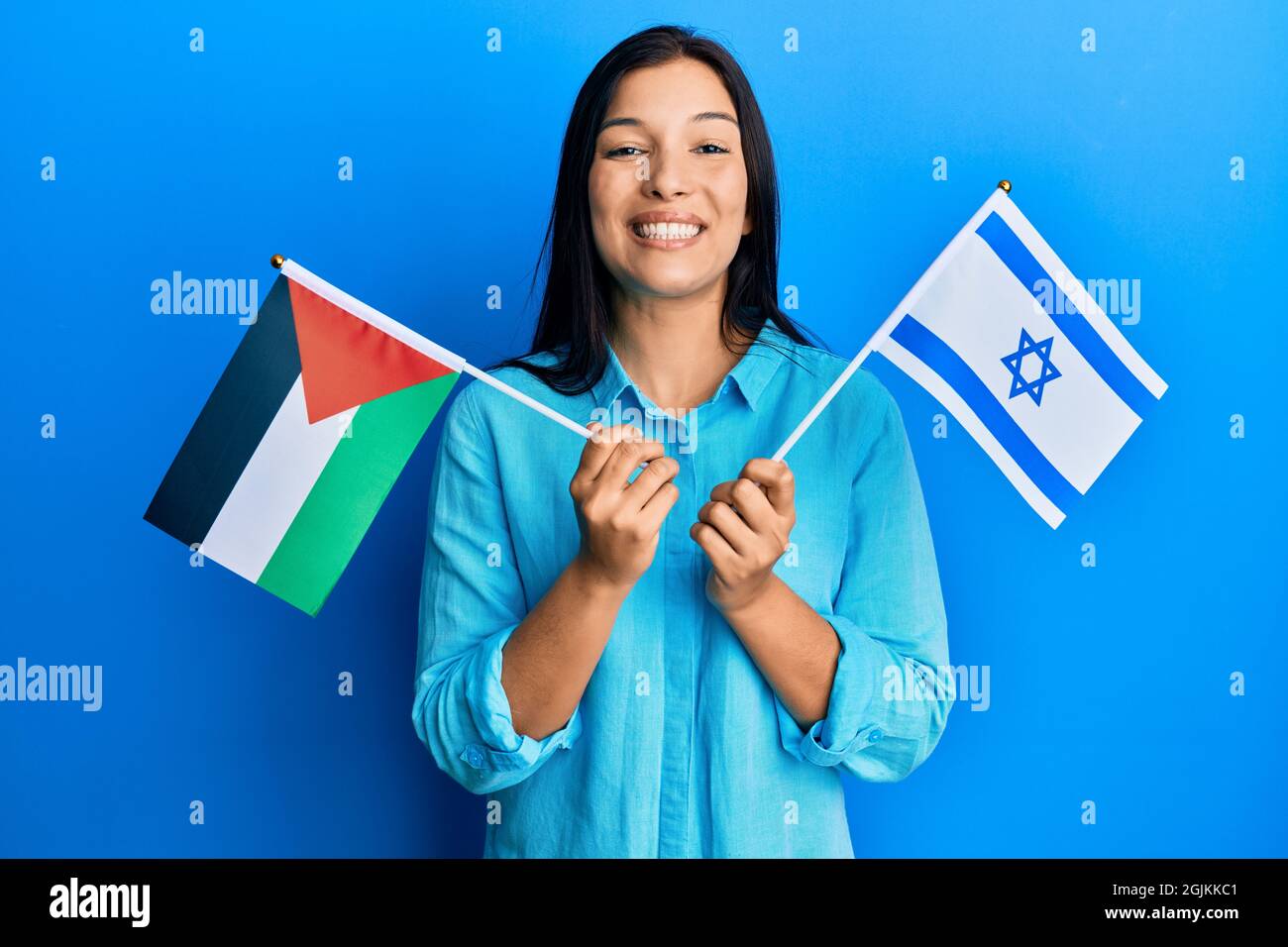 Young latin woman holding palestine and israel flags smiling with a ...