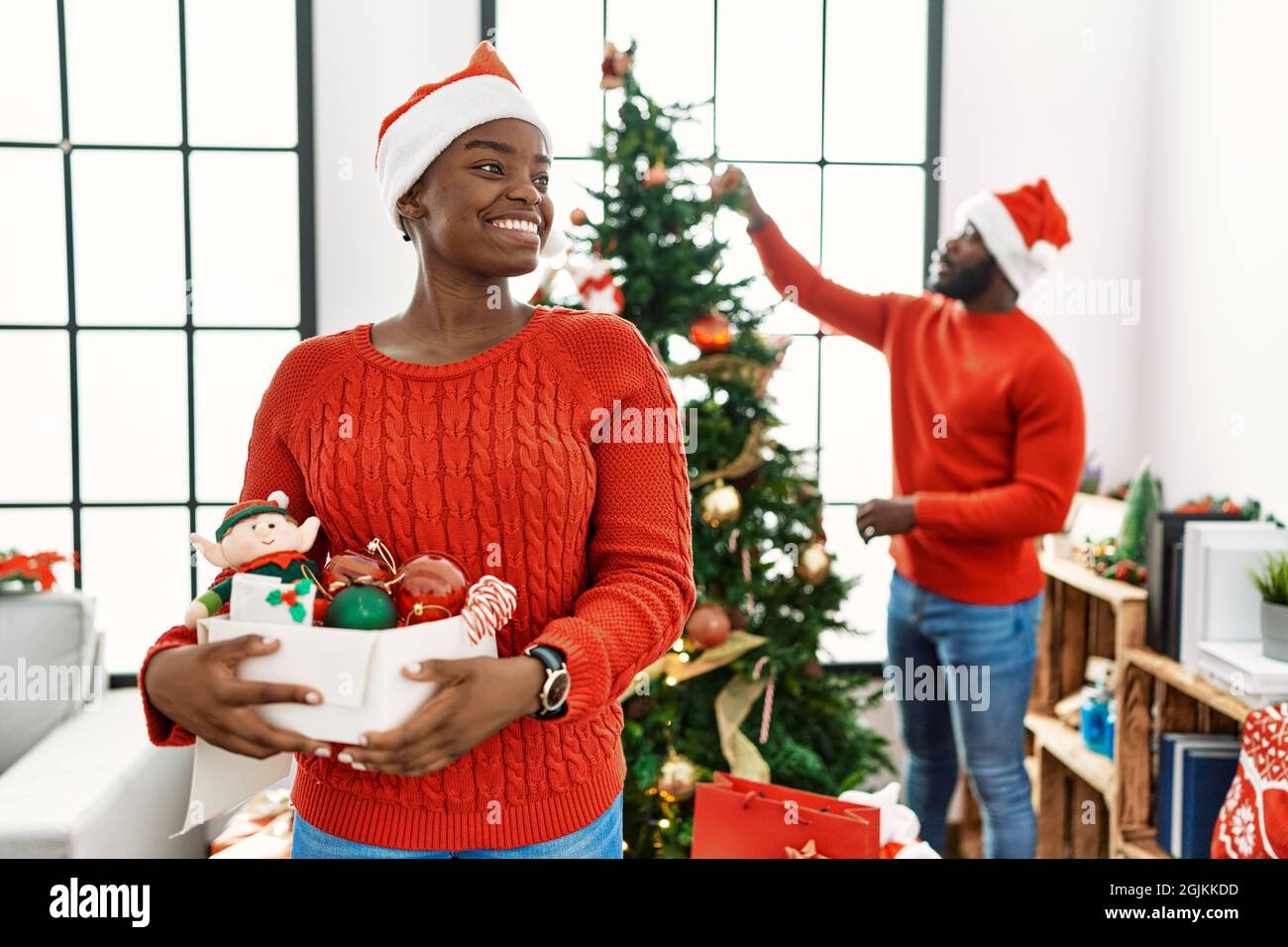 Young african american couple standing by christmas tree looking away ...