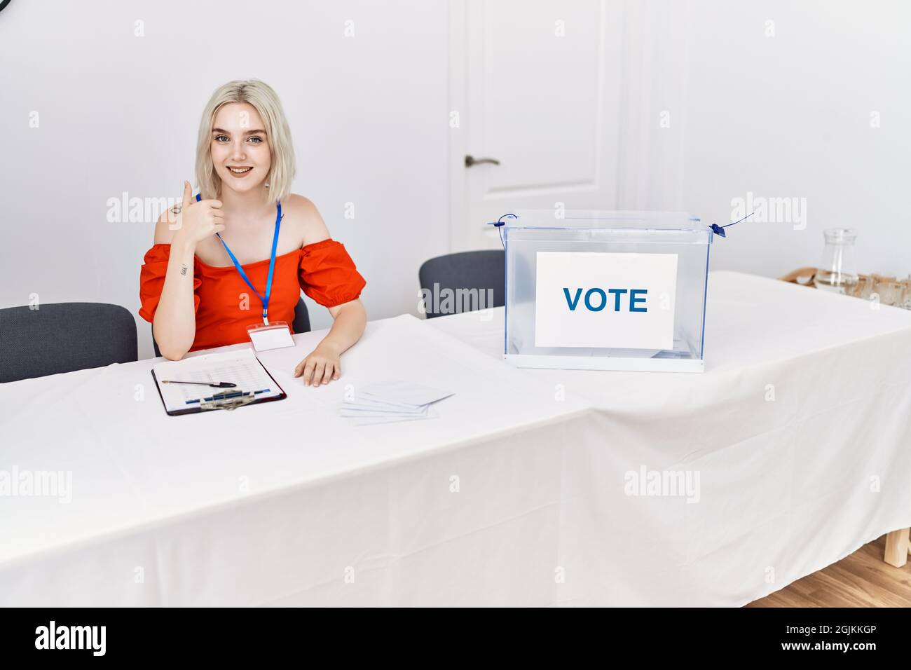 Young caucasian woman at political election sitting by ballot smiling ...