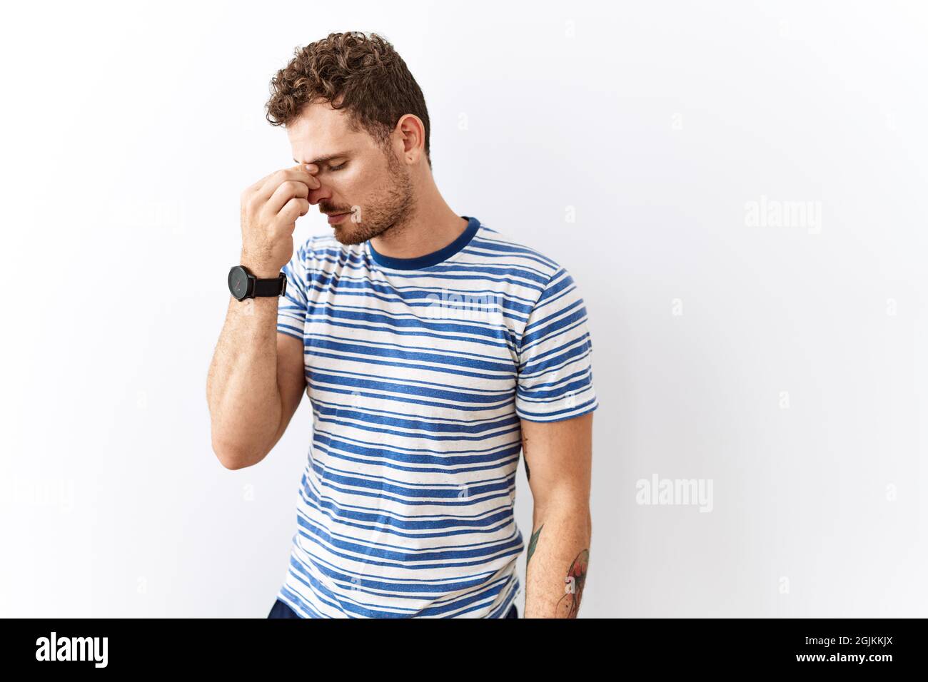 Handsome young man standing over isolated background tired rubbing nose ...