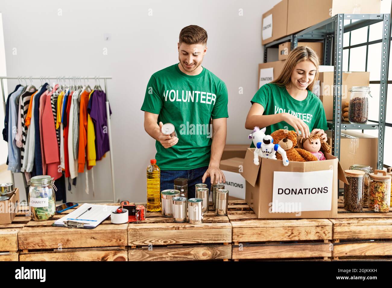 Young hispanic volunteer couple smiling happy working at charity center ...